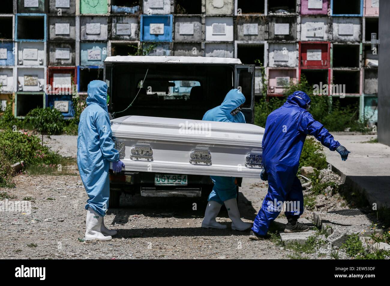 Workers wearing protective equipment bring a casket inside the Baesa ...
