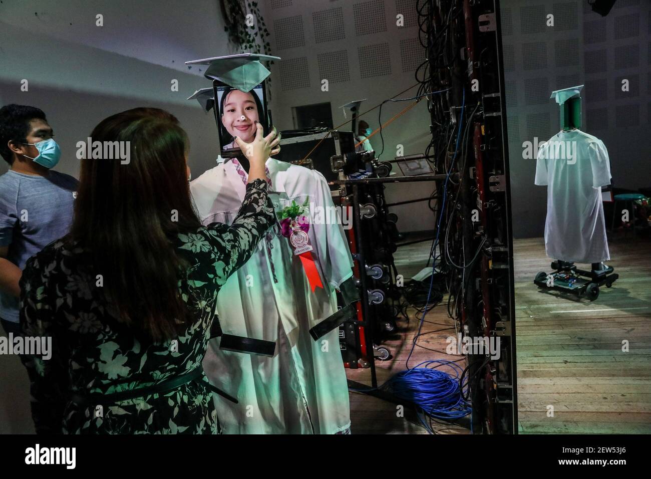 A teacher sets up a tablet attached to a robot wearing a toga during a ...