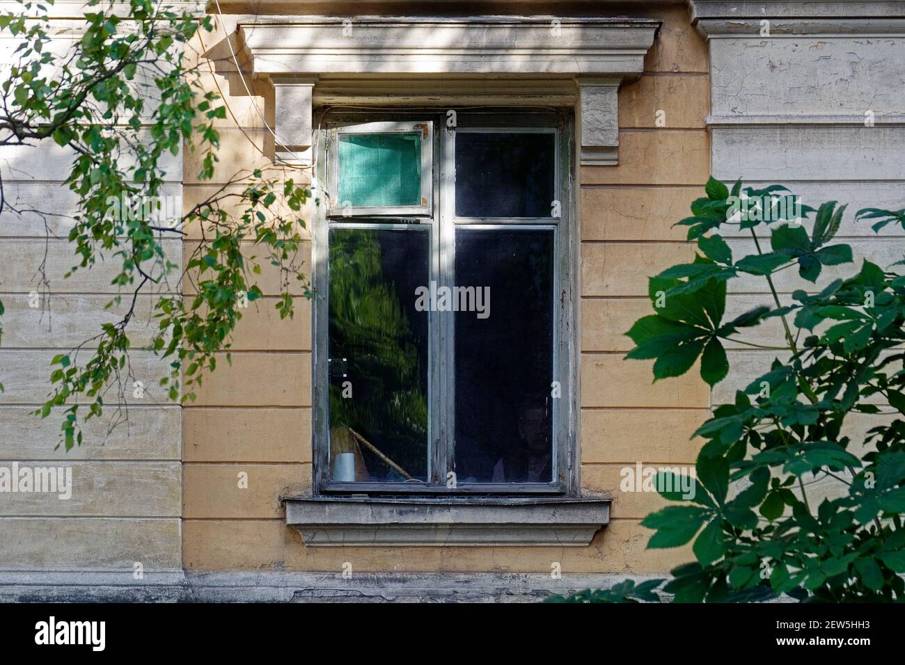 Rectangular dirty window with an old frame with a cornice on a yellow ...