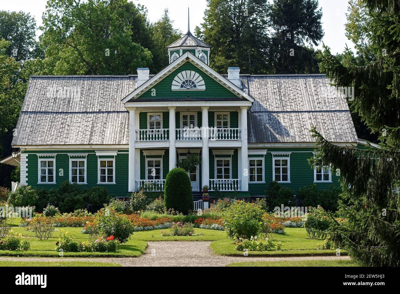 Old green wooden house with a balcony and white columns with flower ...