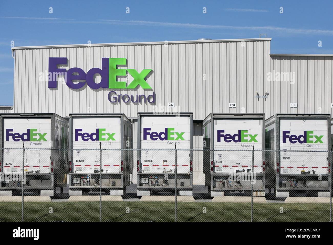 A logo sign and truck trailers outside of a FedEx Ground distribution ...