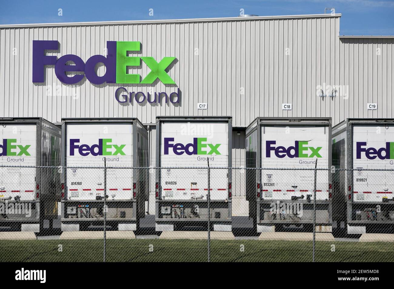 A logo sign and truck trailers outside of a FedEx Ground distribution ...