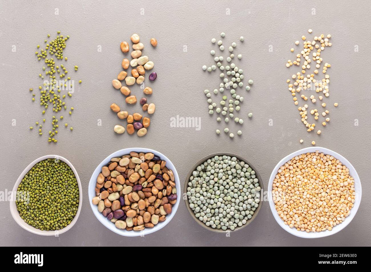 Different types of legumes in bowls and scattered in the background ...