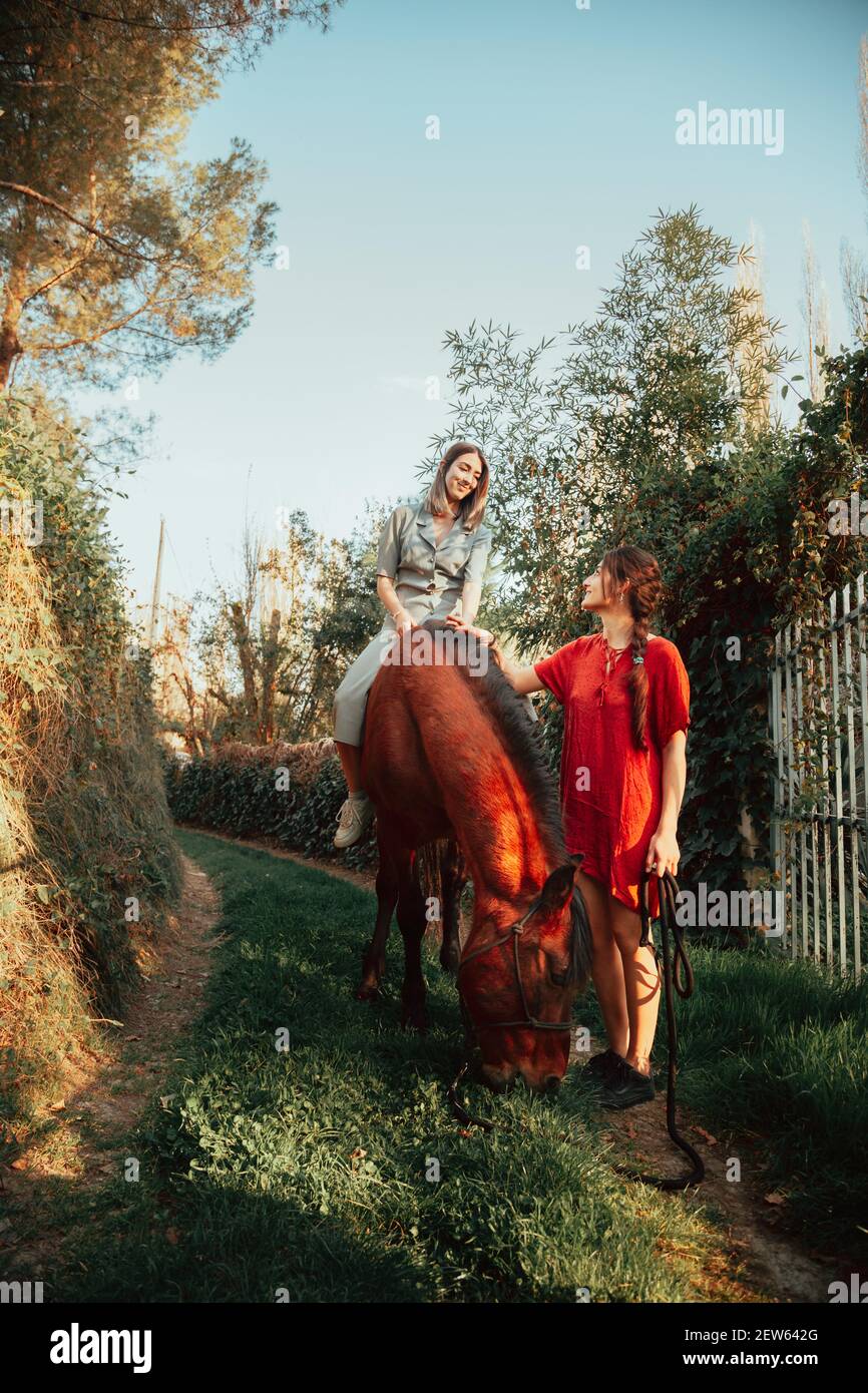 Two women friends chatting and taking a ride with their horse through ...
