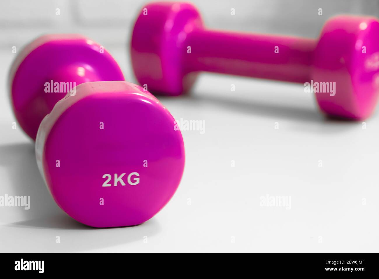 Two styled rubberized pink two-kilogram dumbbells isolated on white ...