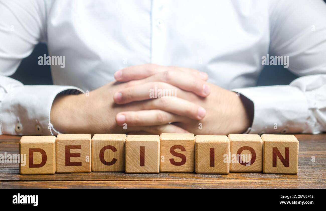 Man folded his hands on a background of blocks with the word Decision ...