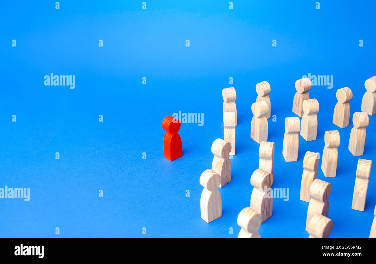 A figurine of a red man stands aside from the crowd of people. Stand ...