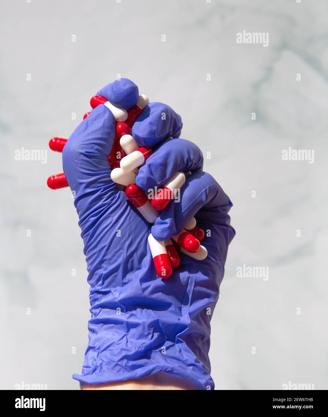 A hand with blue latex gloves grabbing hand full of medicines, Capsules ...
