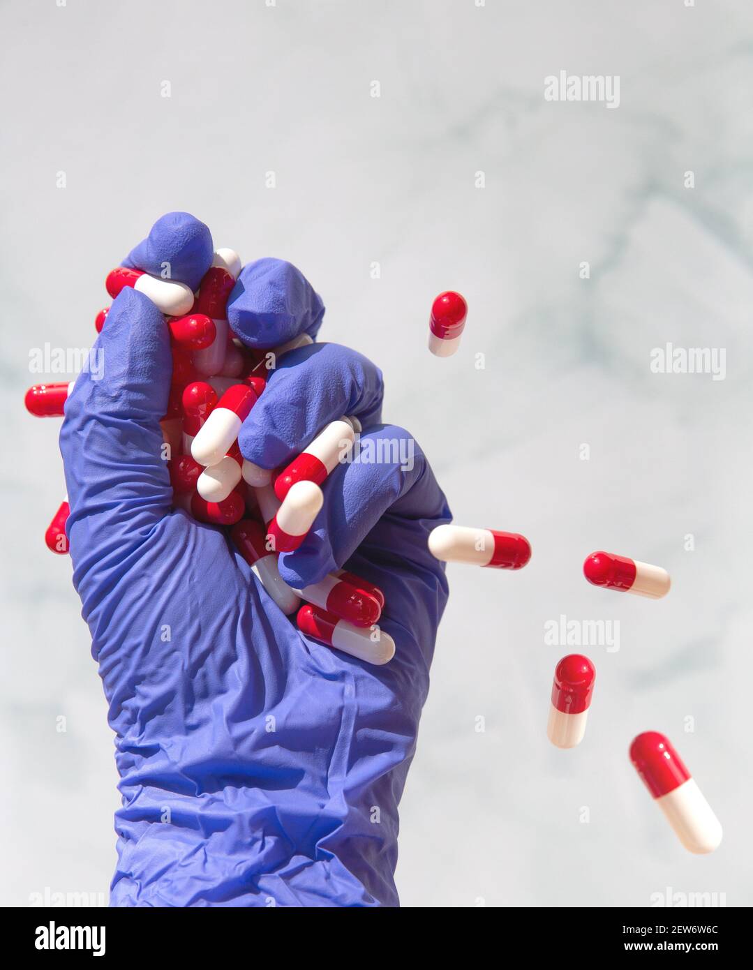 A hand with blue latex gloves grabbing hand full of medicines, Capsules ...