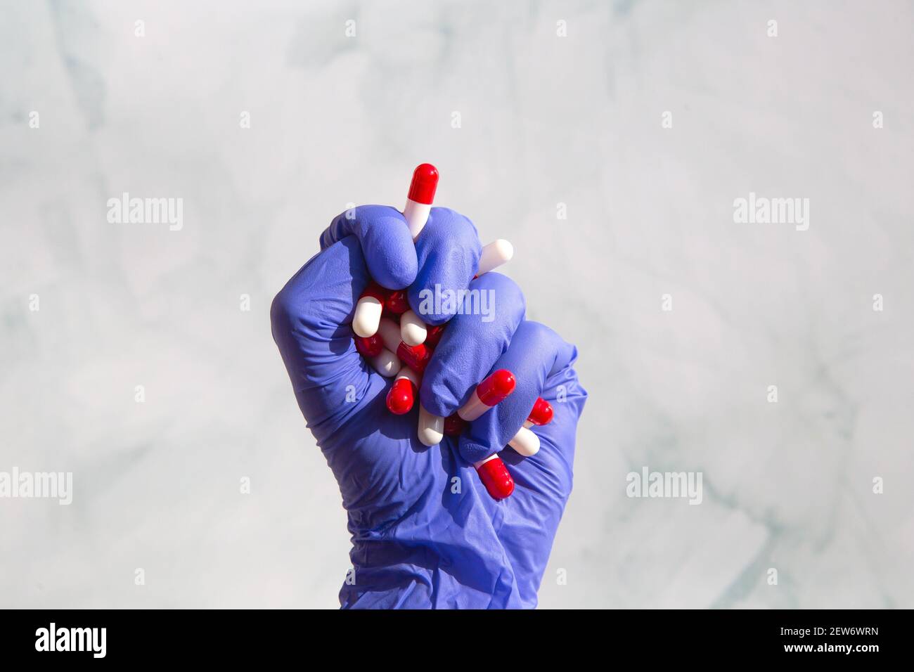 A hand with blue latex gloves grabbing hand full of medicines, Capsules ...