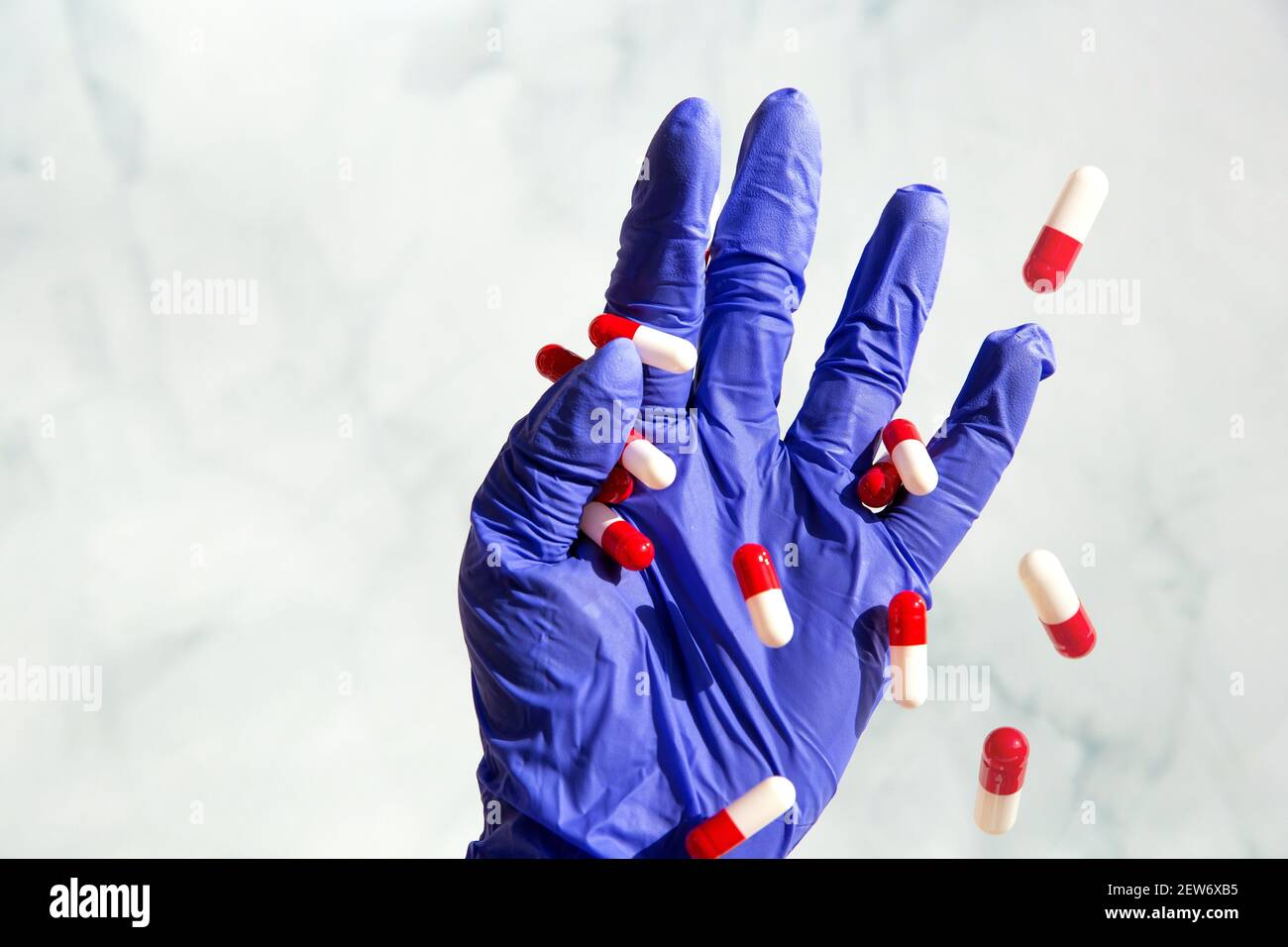 A hand with blue latex gloves grabbing hand full of medicines, Capsules ...