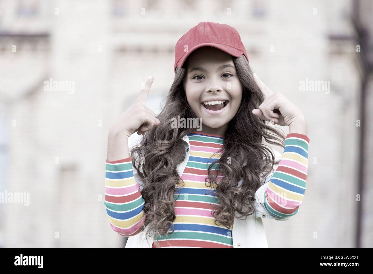 Use your brain. Happy child point fingers up outdoors. Small child wear ...