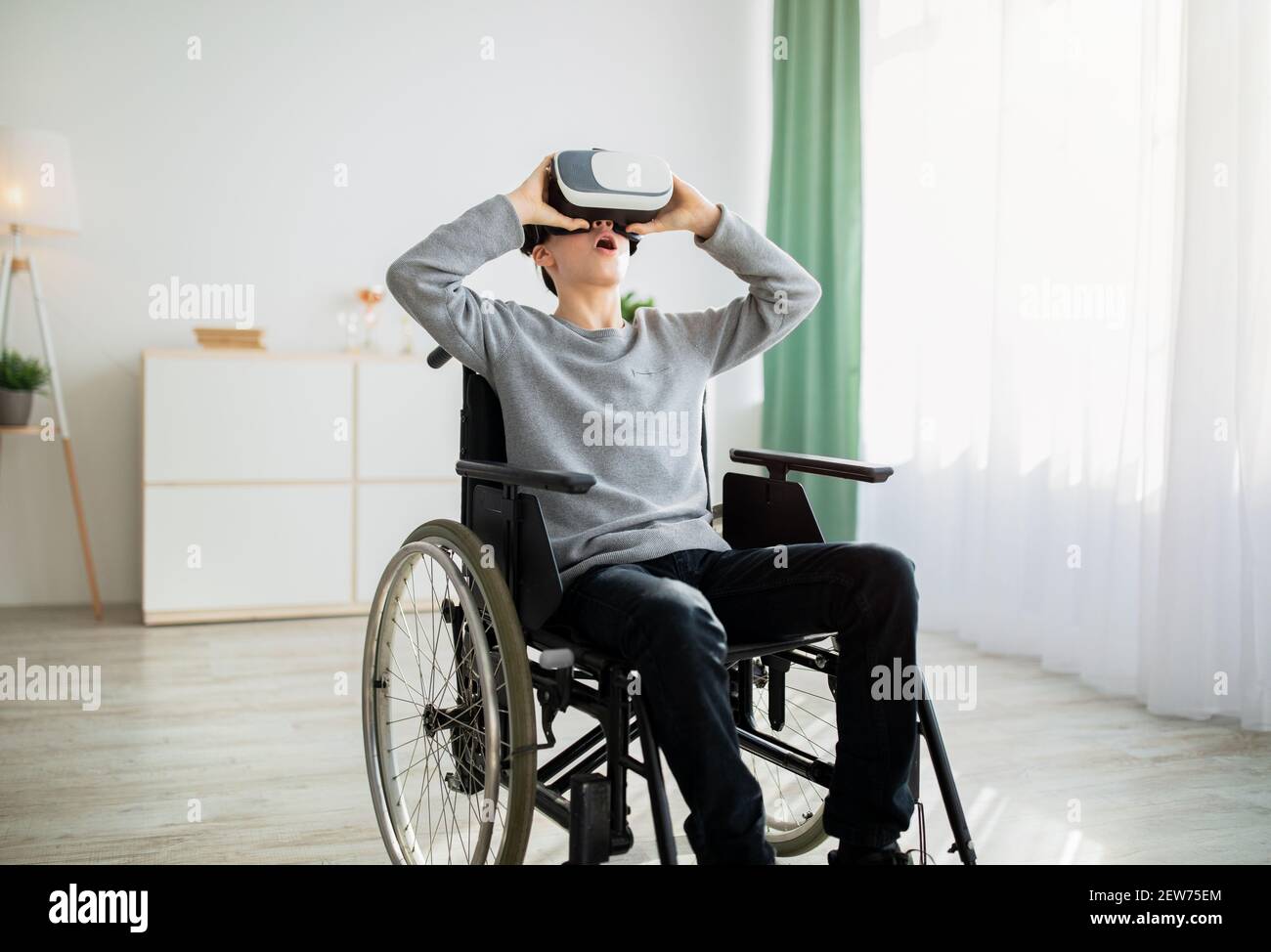 Happy handicapped teen boy in wheelchair using VR headset to explore ...