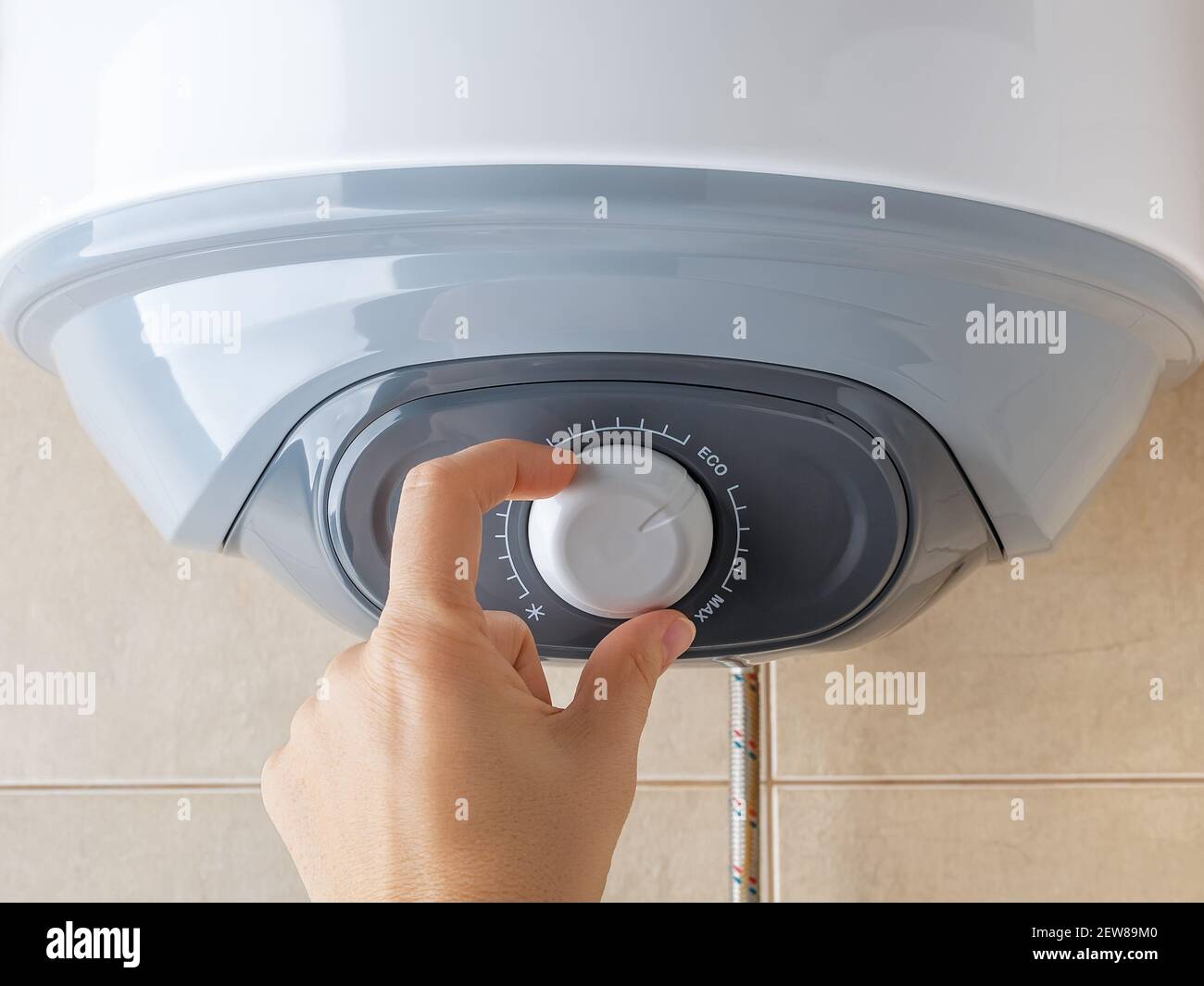 Woman hand rotates water heater temperature adjuster to the Eco ...
