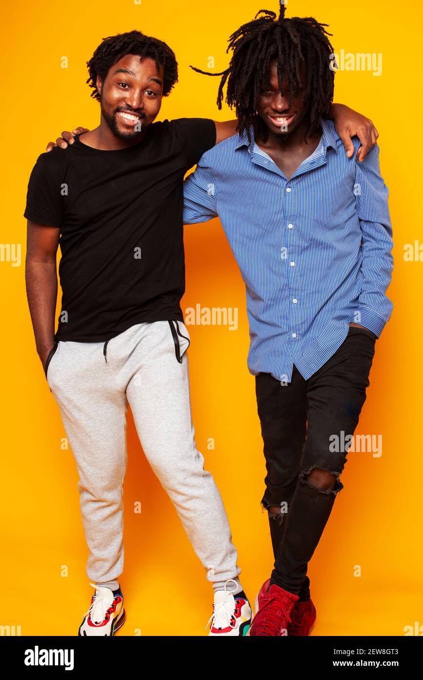 two african american guys posing cheerful together on yellow background ...