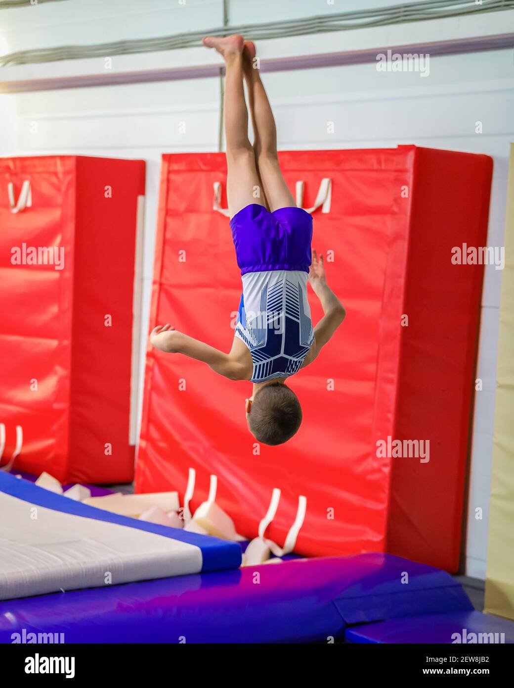 A young guy performs a jump somersault, in training. Gymnastics Stock ...