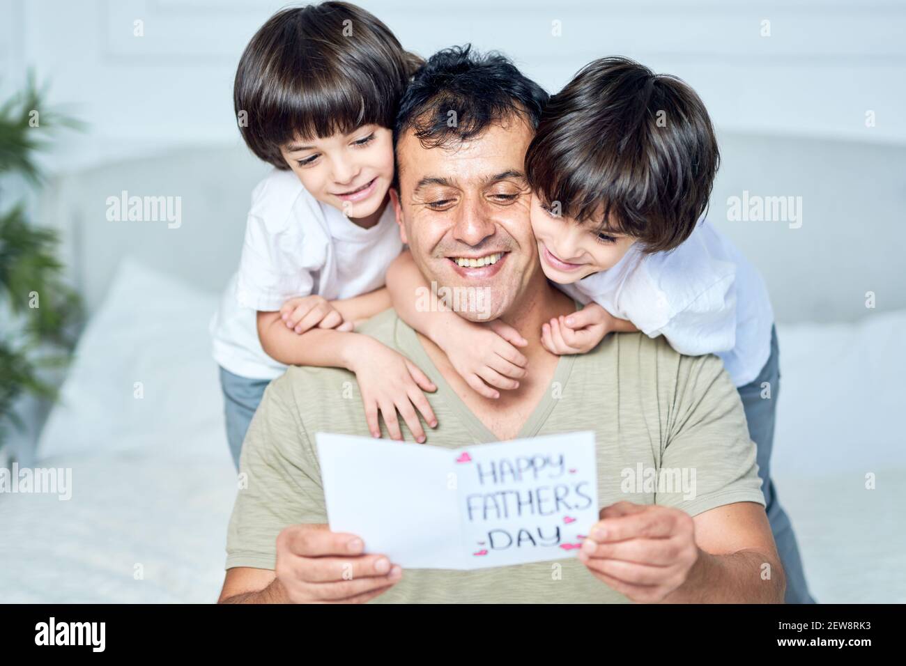 Portrait of latin father looking happy while his two little boys ...