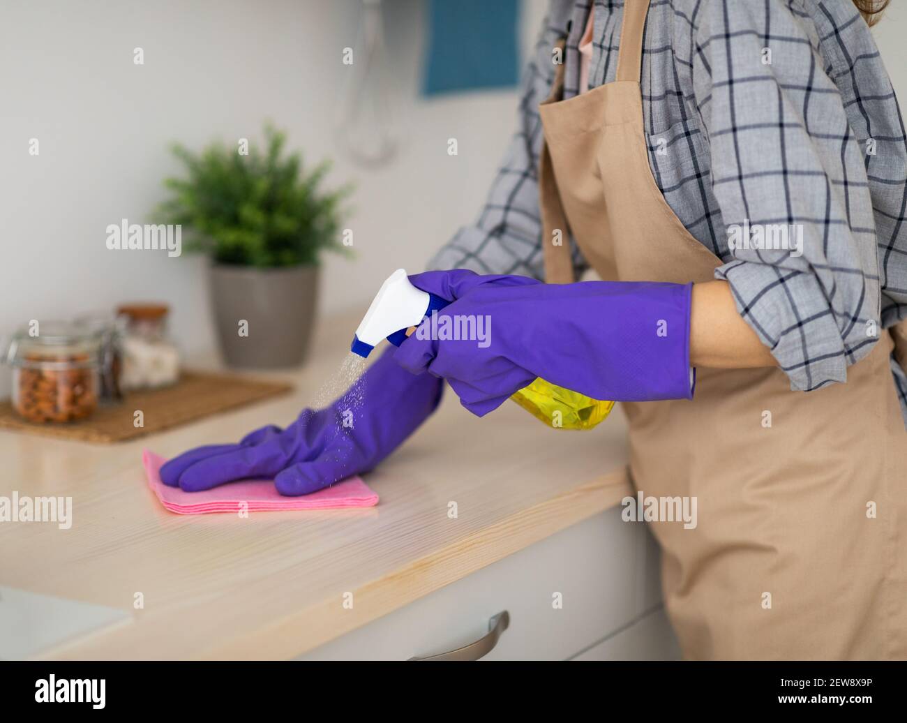 Unrecognizable housemaid with detergent cleaning kitchen table, closeup ...