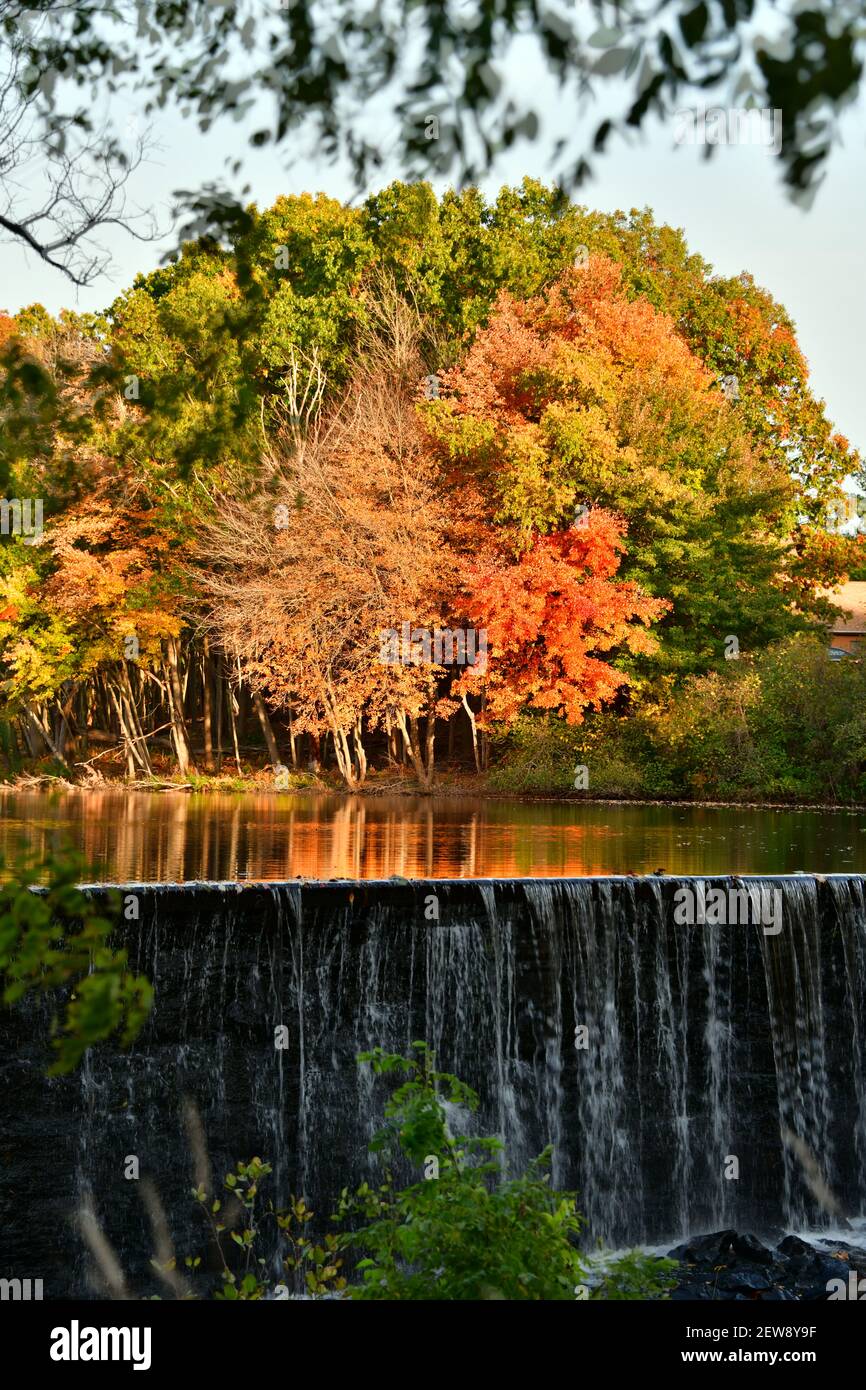 A brilliant foliage display reflected in a lake with a waterfall during ...
