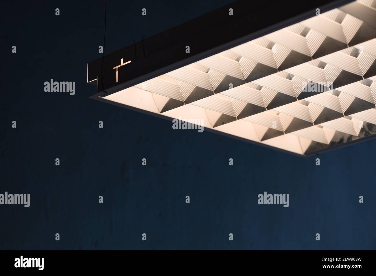 Office interior detail. Fluorescent lamp hanging from dark ceiling copy ...