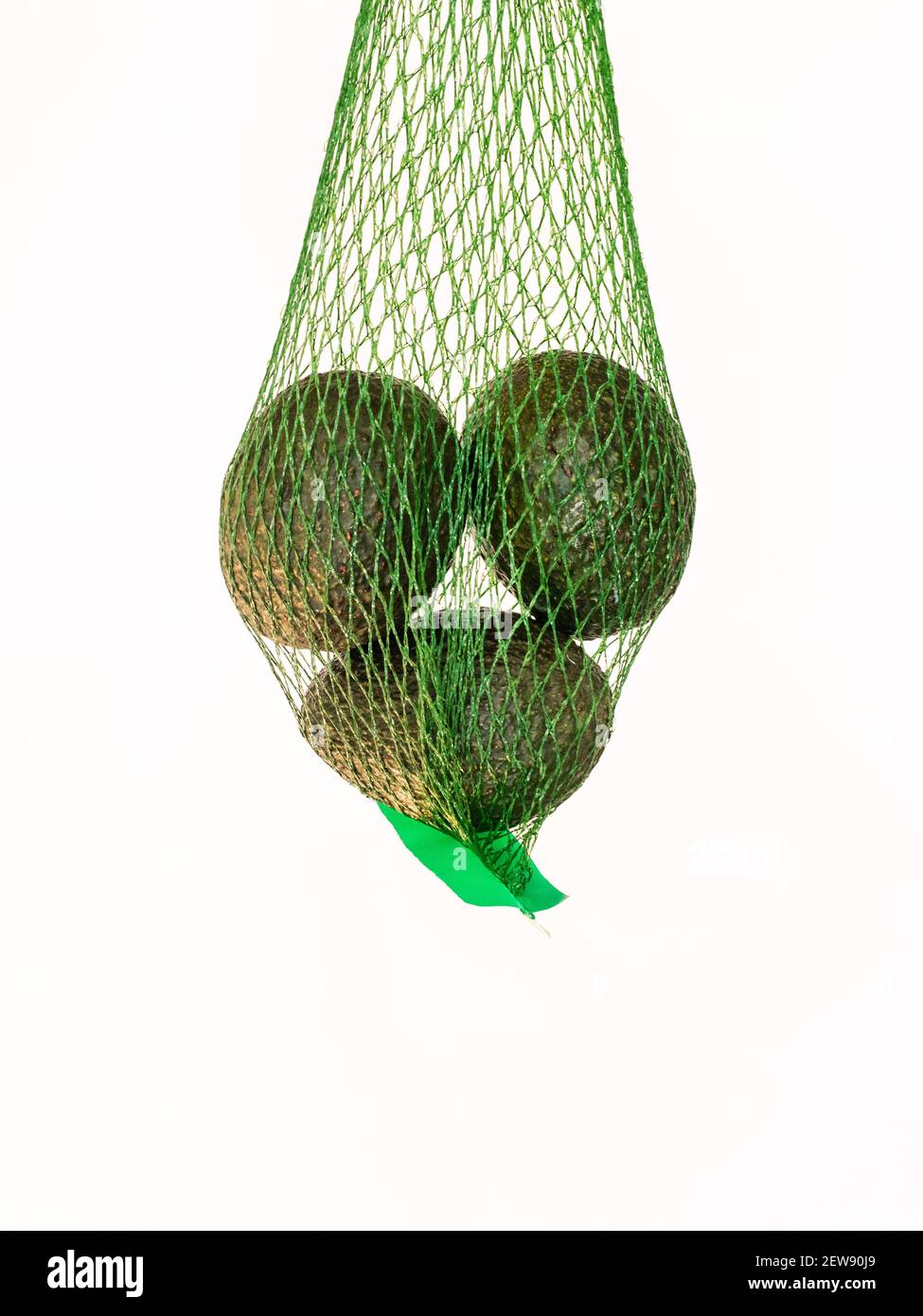 Avocados in a green net isolated and suspended on air with a white ...