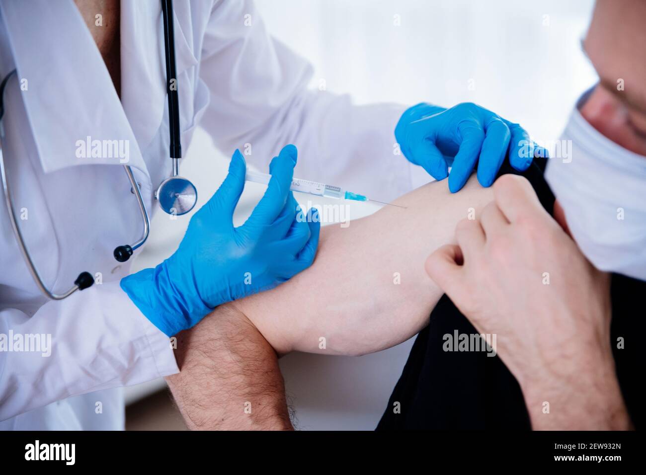 Doctor injecting vaccination in arm of man patient Stock Photo - Alamy