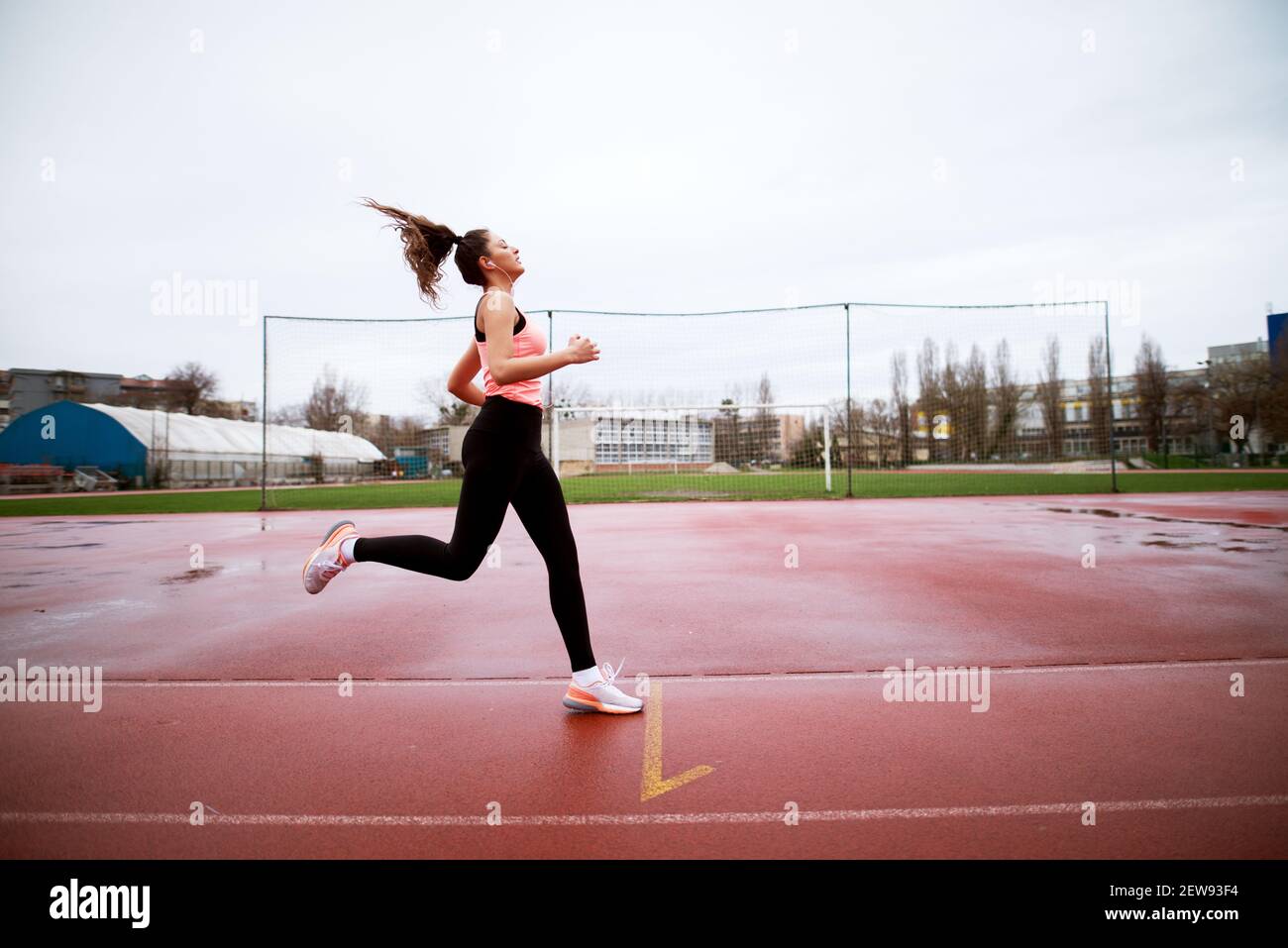 Attractive young focused fitness girl arriving at the finish line after ...