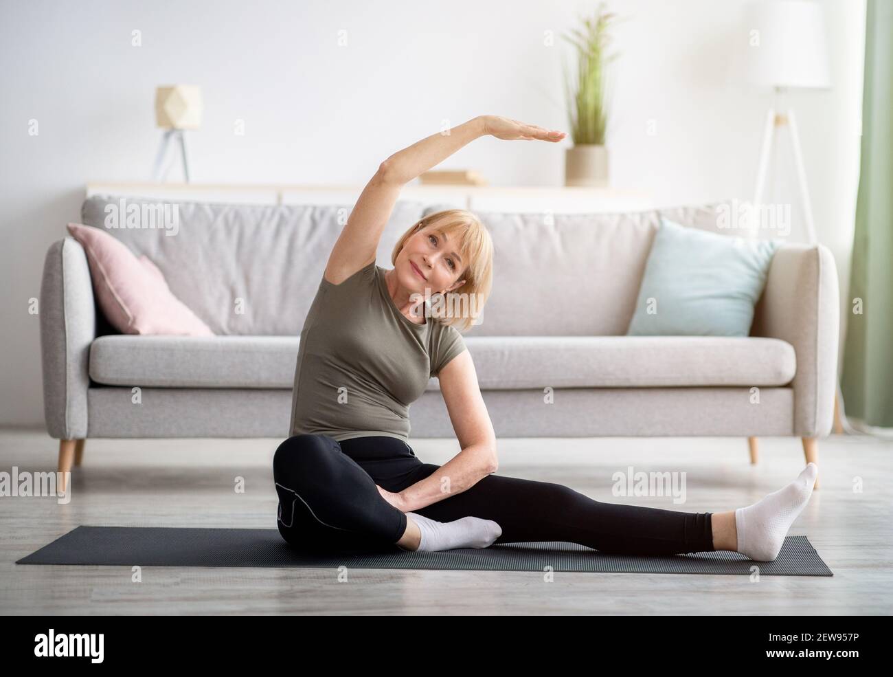 Full length portrait of athletic mature woman stretching her leg on ...