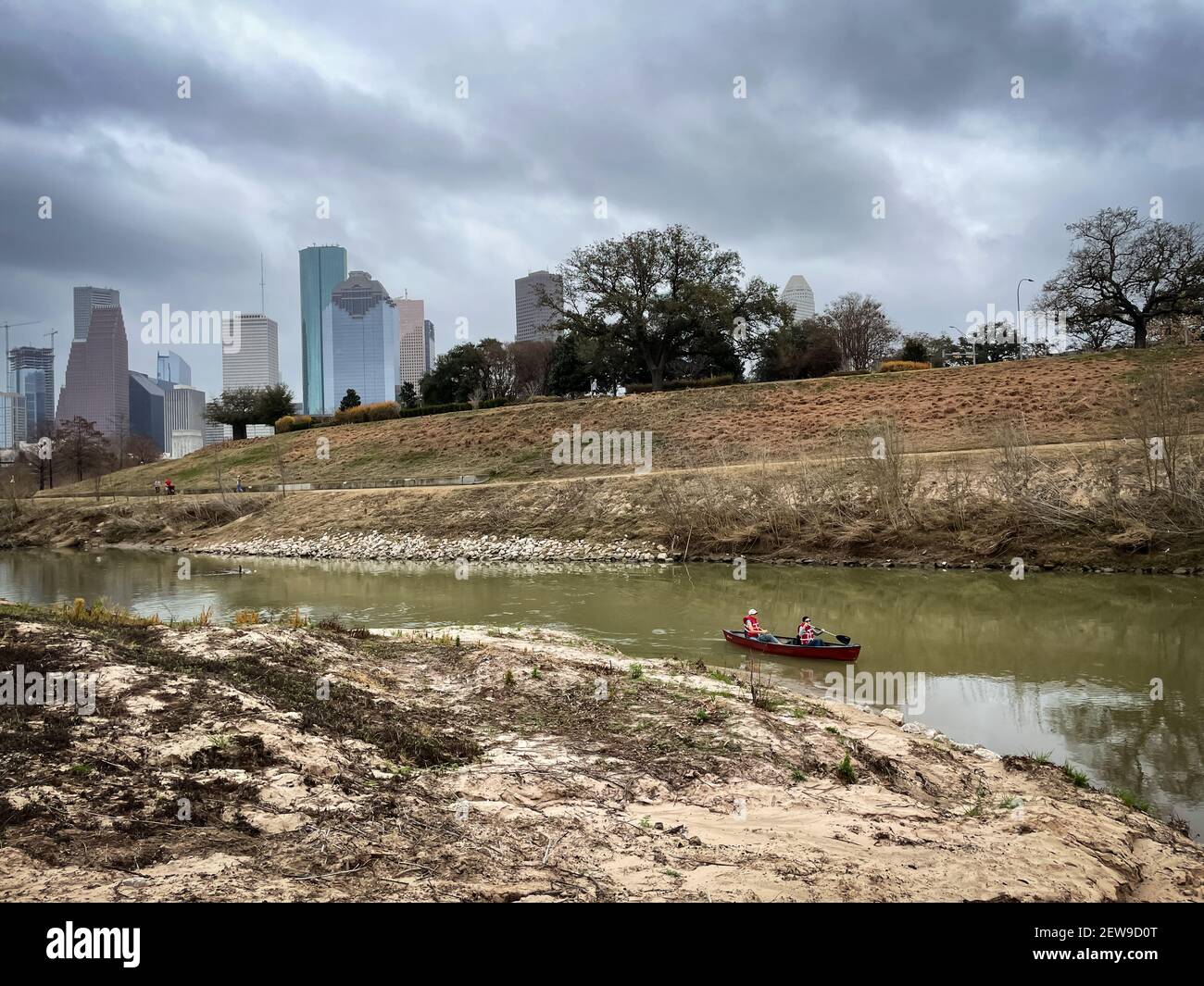 A view of Buffalo Bayou Park with people boating on the front and ...
