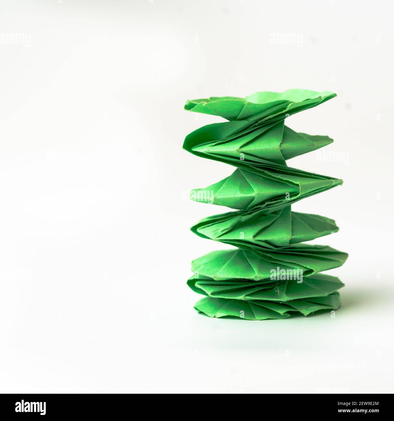 A green cylindrical origami spring isolated on a white background Stock ...
