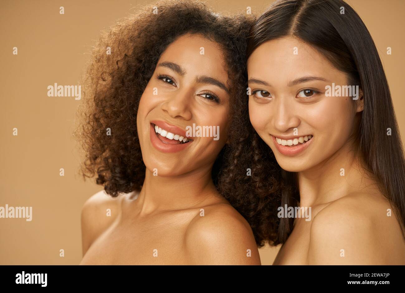 Portrait of two joyful attractive mixed race young women with perfect ...