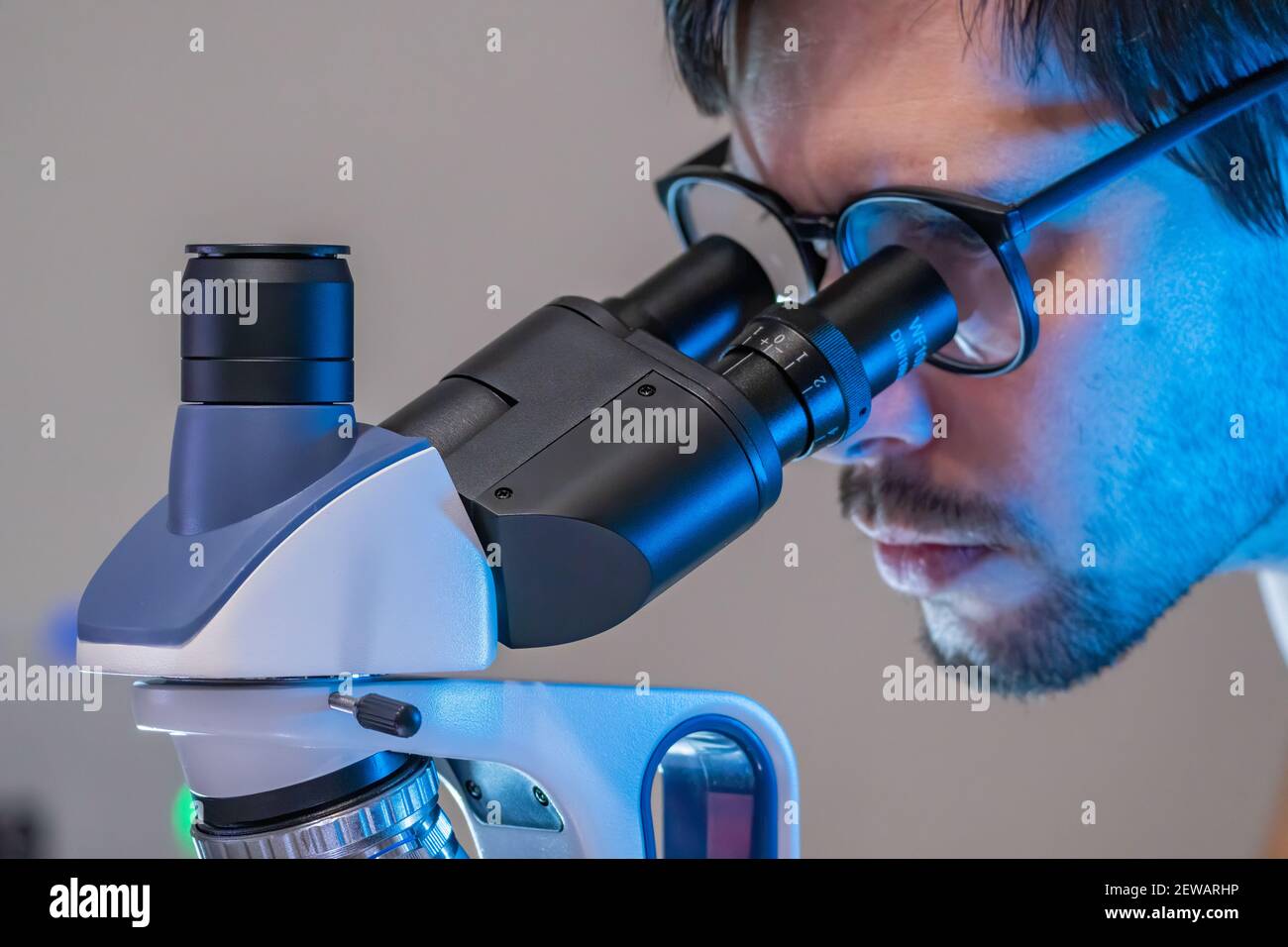 Young scientist in laboratory is looking inside microscope ...
