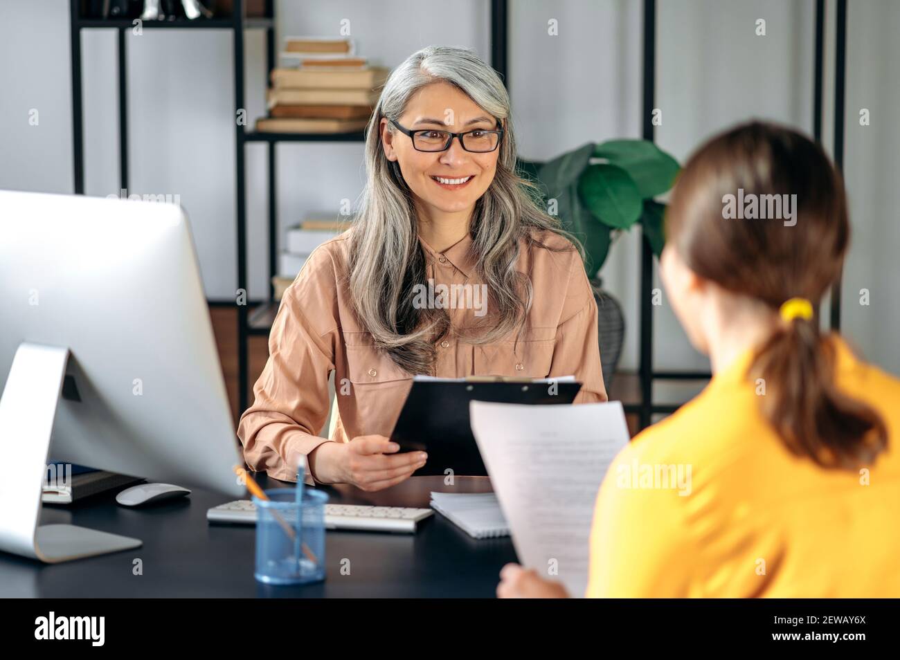 Friendly female mature hr manager listening and looks a resume of a new ...