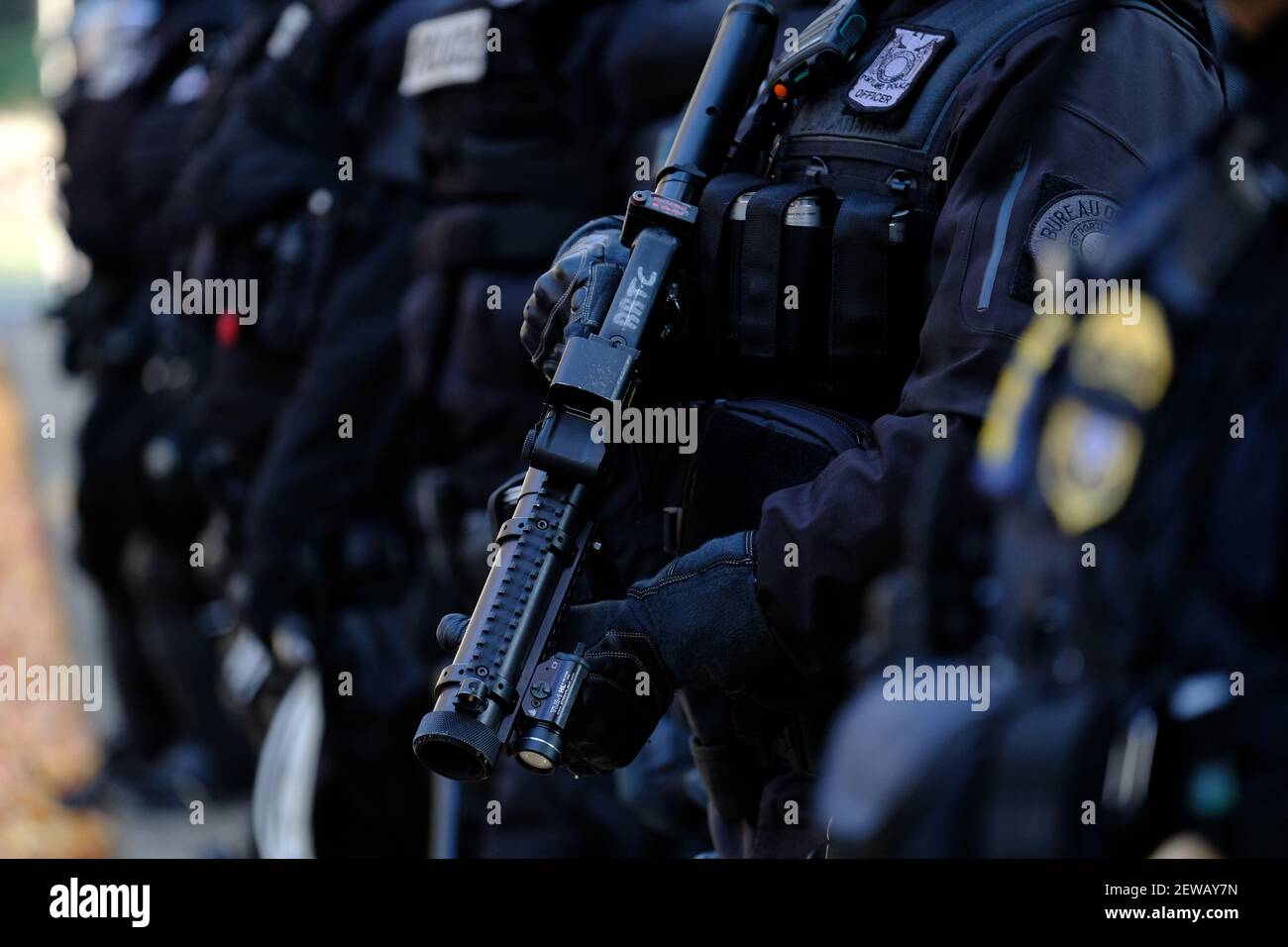 Police officers in riot gear carrying crowd control weapons monitors ...