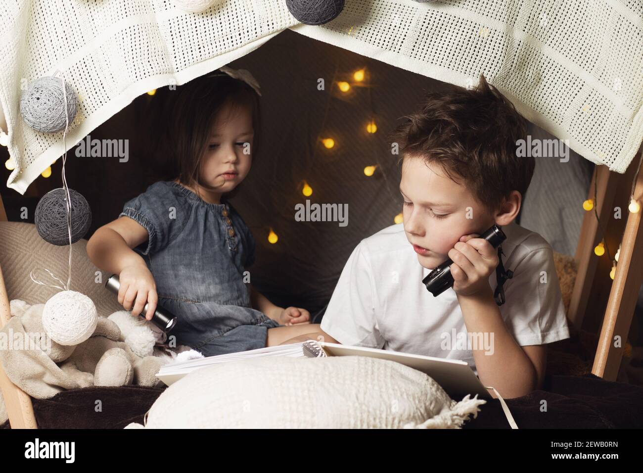Siblings Lie In Hut Of Chairs And Blankets Brother And Sister Reading