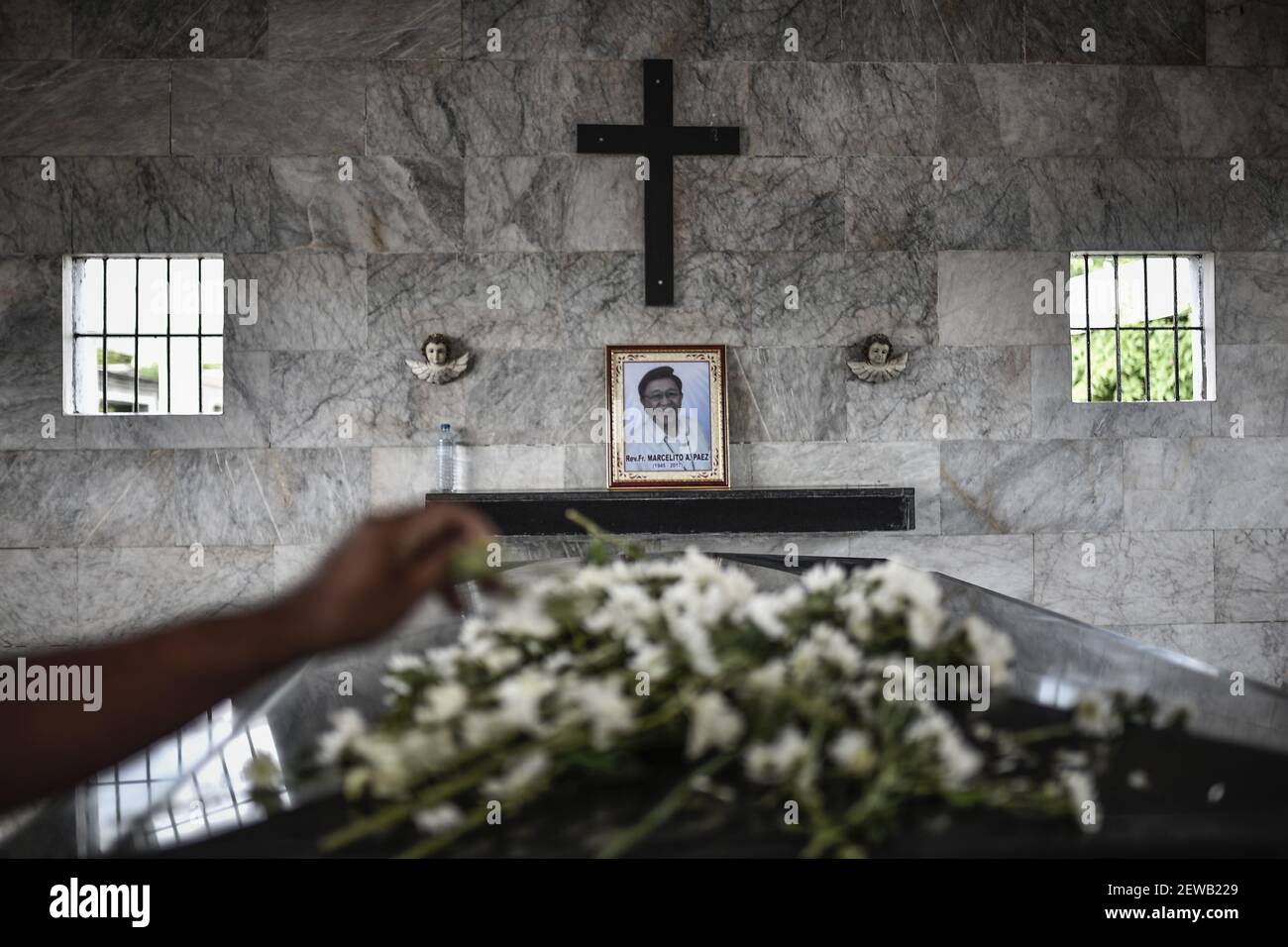 A relative places a flower on the tomb of activist priest Fr. Marcelito ...