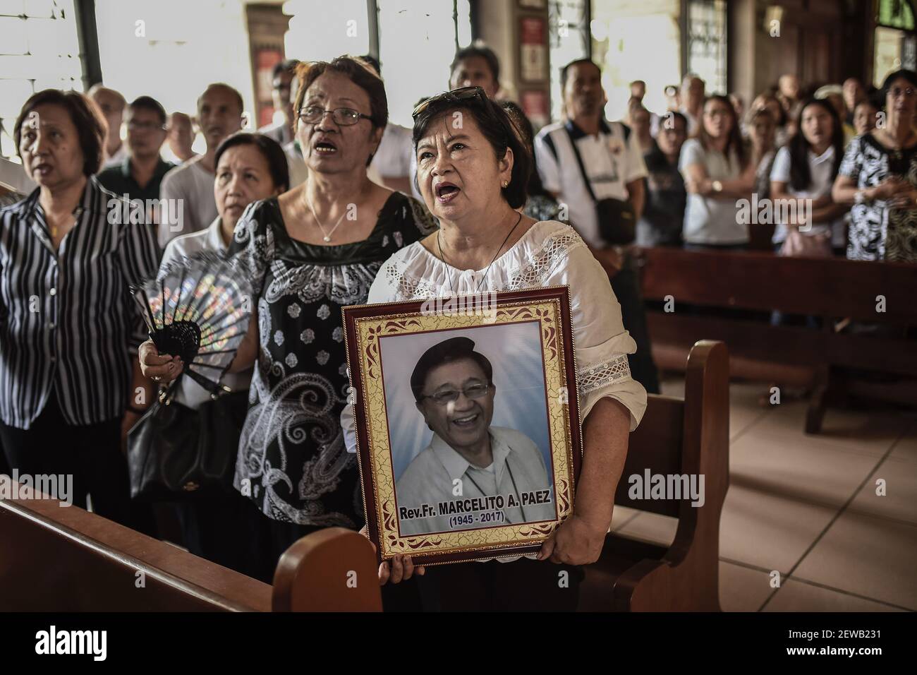 A relative holds a picture of activist priest Fr. Marcelito "Tito" Paez ...