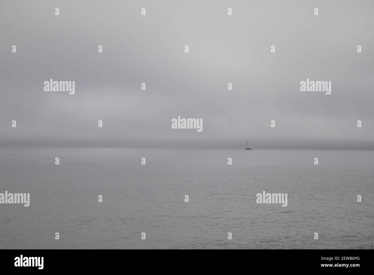 A single lone sailboat floating on the horizon off the coast of Long ...