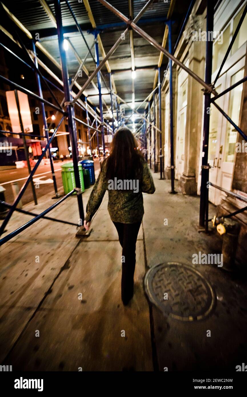 Woman walking under scaffolding on a dark New York street Stock Photo ...