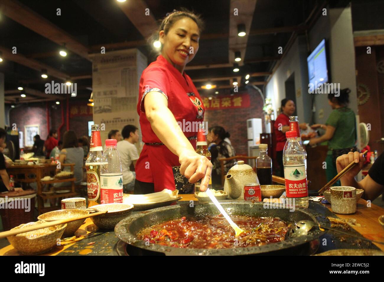 --FILE--A Chinese waitress serves customers to enjoy a spicy hot pot at ...