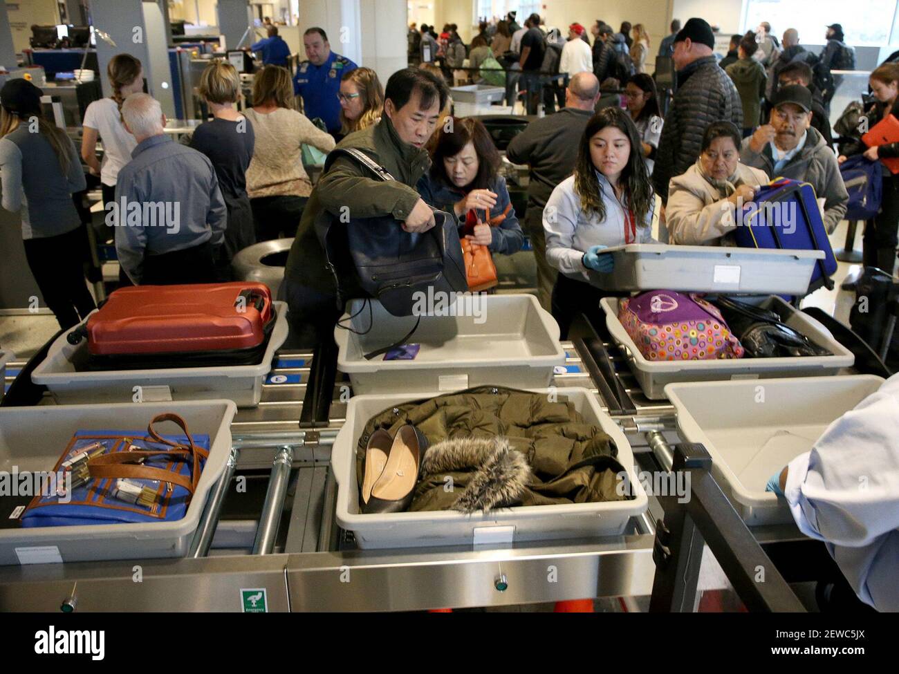 Arriving airline passengers place their items into bins at the ...
