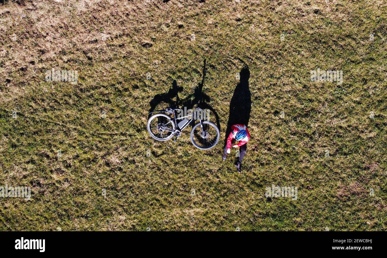 Aerial shot with drone of female cyclist with bike on meadow with light ...