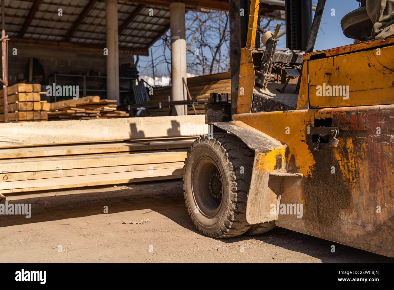 Fork lifter at warehouse lifting timber planks in sunny day no people ...