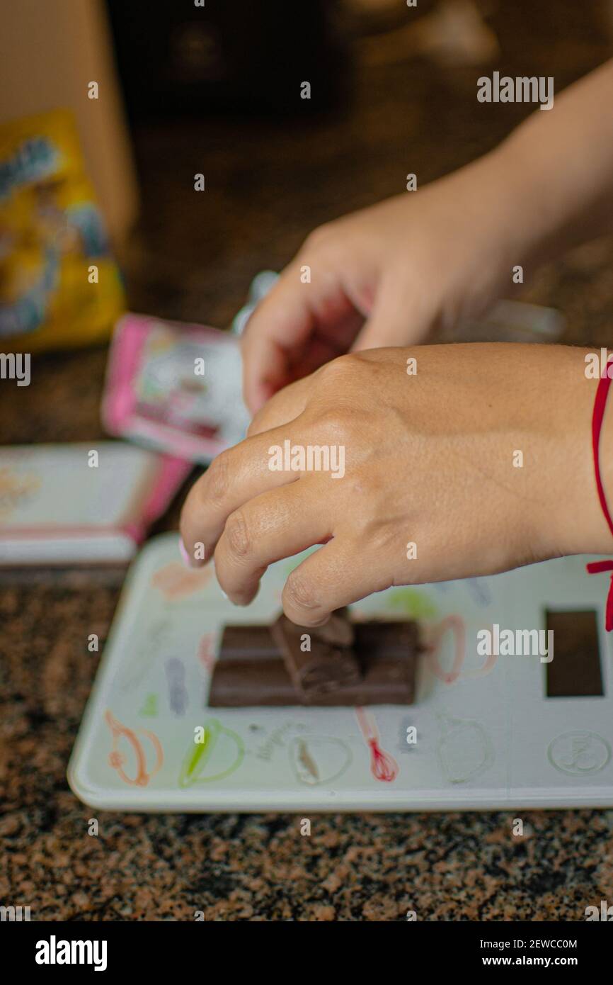 A female putting chocolate into a kitchen scale Stock Photo - Alamy