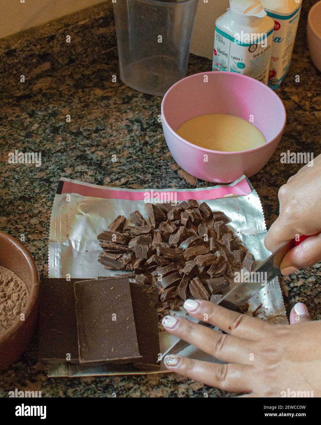 A female hands chopping dark chocolate bar with a knife Stock Photo - Alamy