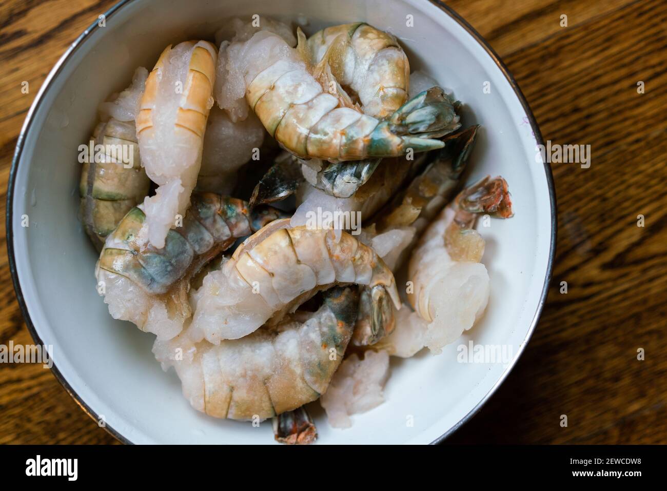 A top view shot of raw king prawn tails with cut shells in a ceramic ...