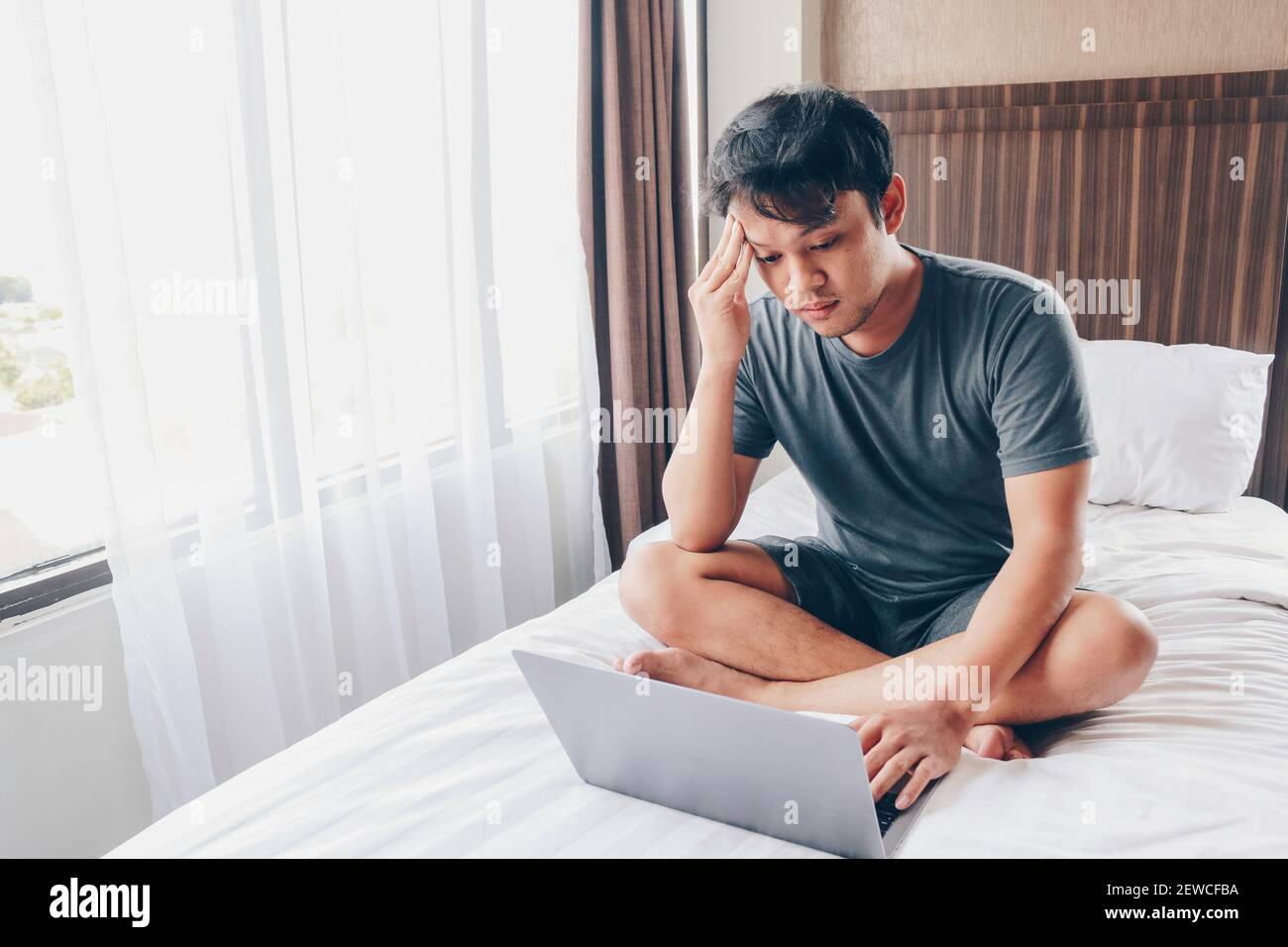 Tired stressed young Asian man feeling sleepy and tired while using ...