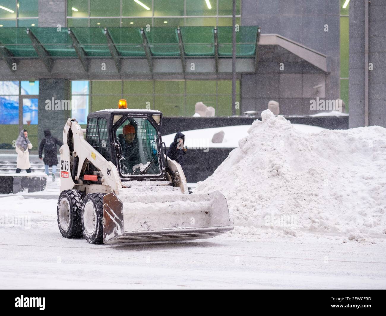 Moscow. Russia. February 12, 2021. A small loader excavator with a ...