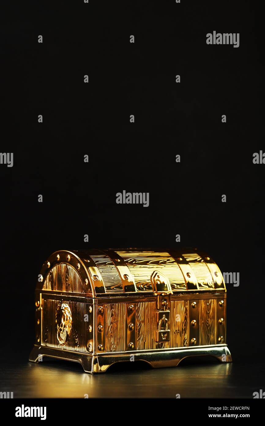 Gold treasure chest on a black textured background. Closed box with ...