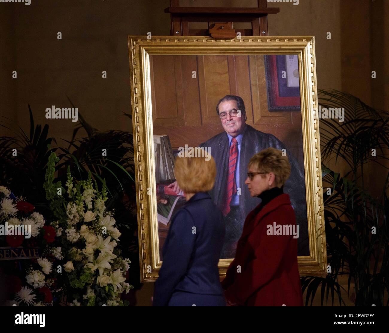 Guests walk by a portrait of Supreme Court justice Antonin Scalia as ...